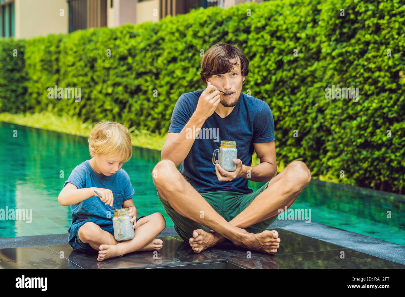 Father and son eat dessert with chia seeds and mangoes by the pool in ...
