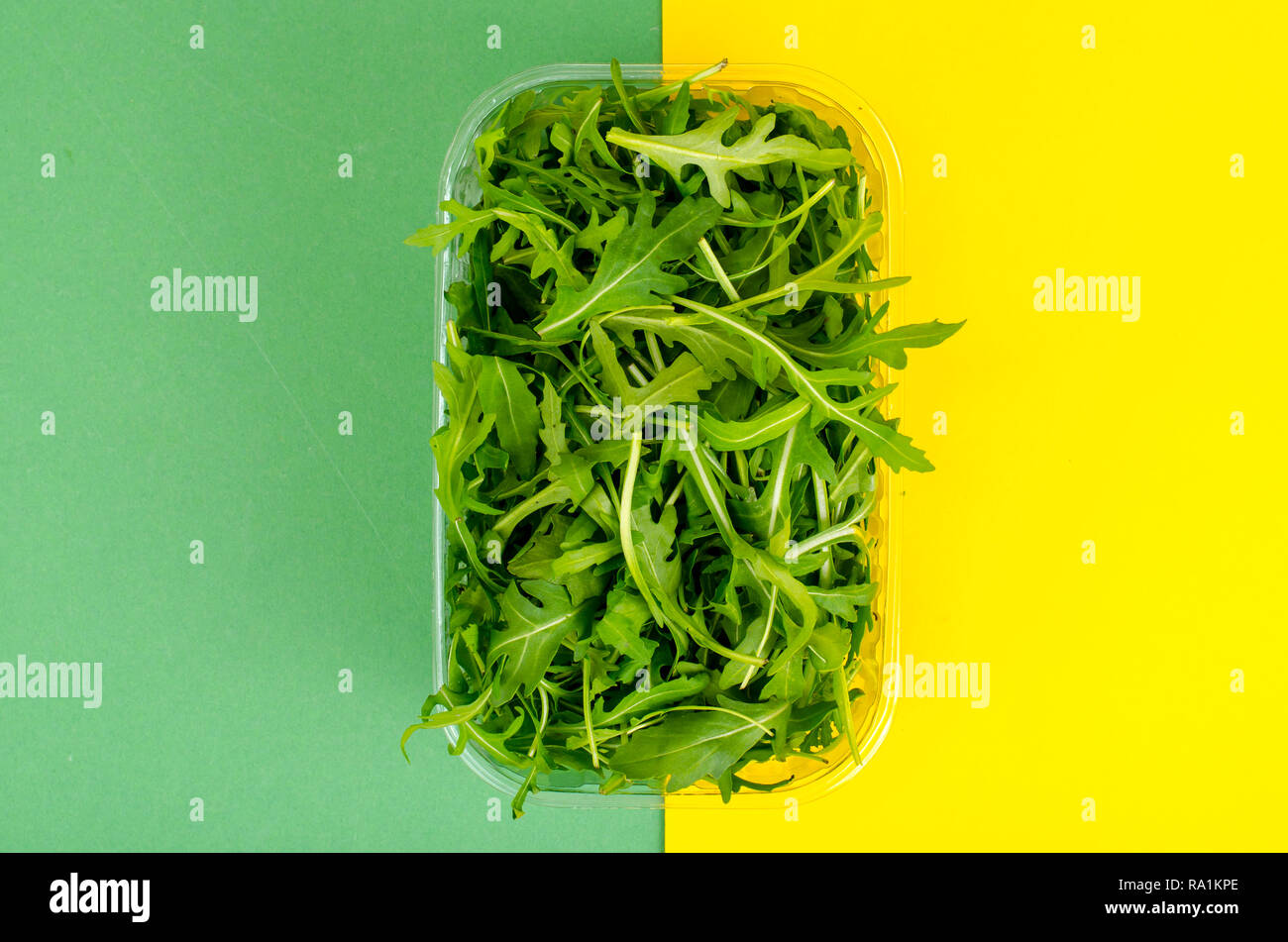 Fresh green arugula in package on color background. Studio Photo Stock ...