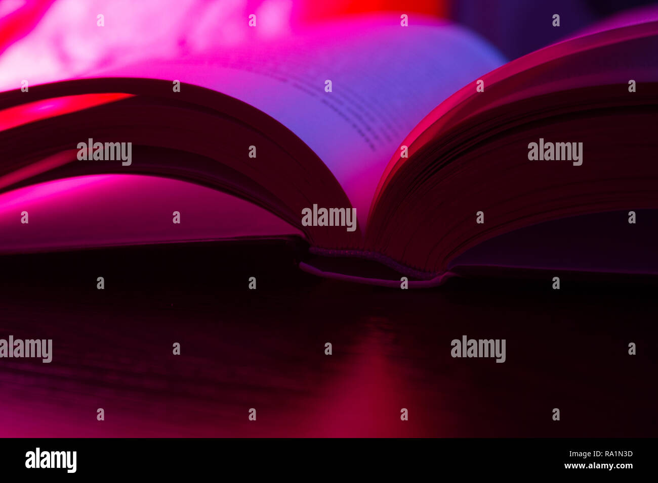 Open book with pink neon light over dark background Stock Photo - Alamy