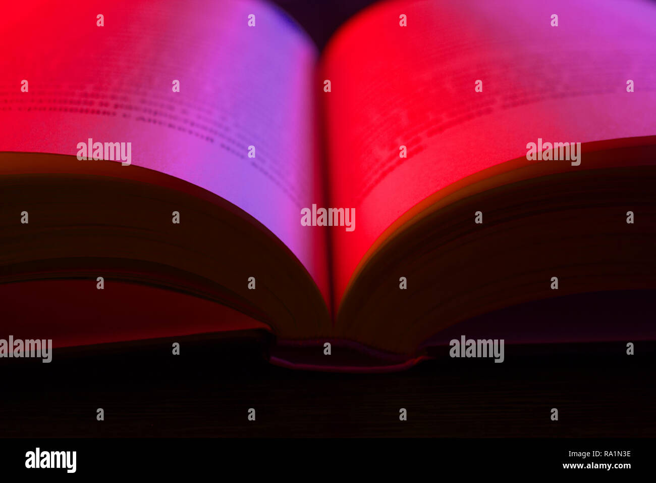 Open book with pink neon light over dark background Stock Photo - Alamy