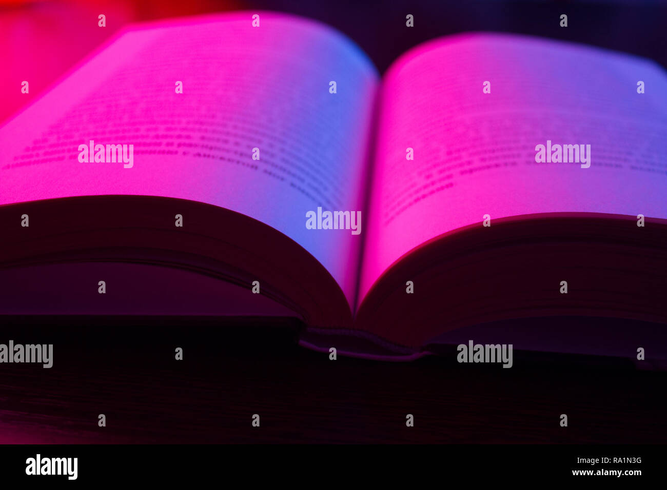 Open book with pink neon light over dark background Stock Photo - Alamy