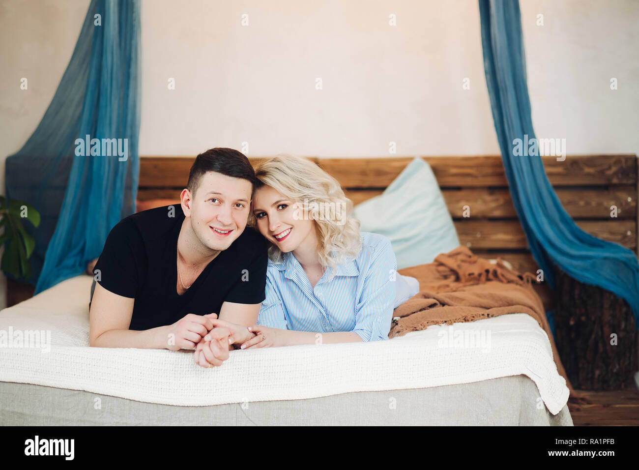 Young couple laying together on belly in white bed Stock Photo - Alamy