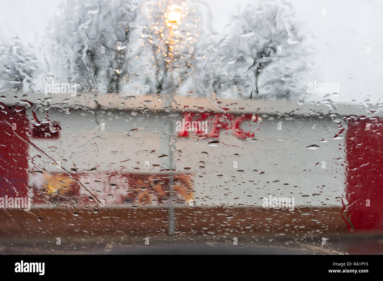 A blurred side of a KFC outlet seen through a rain spattered car window ...