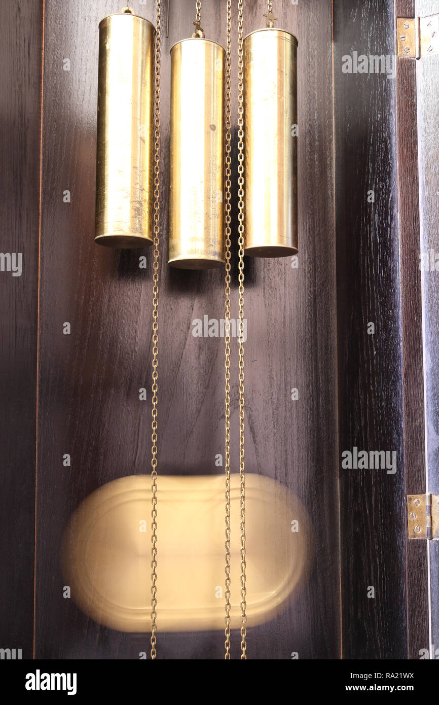 The motion blur of a golden round pendulum clock weight moving inside a ...