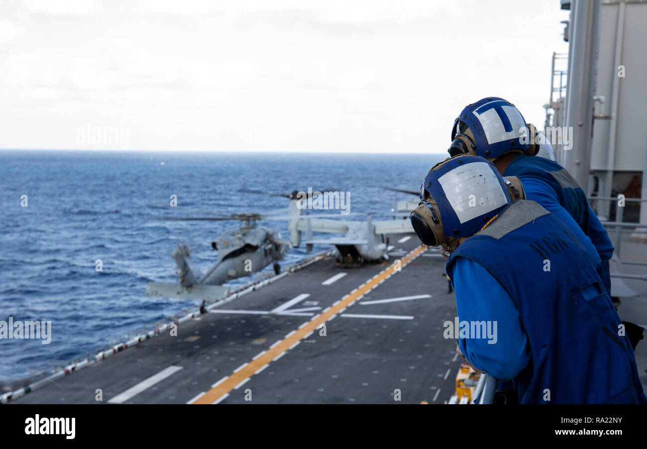 U.S. Navy Sailors observe as a MH-60 Seahawk takes off from the flight ...