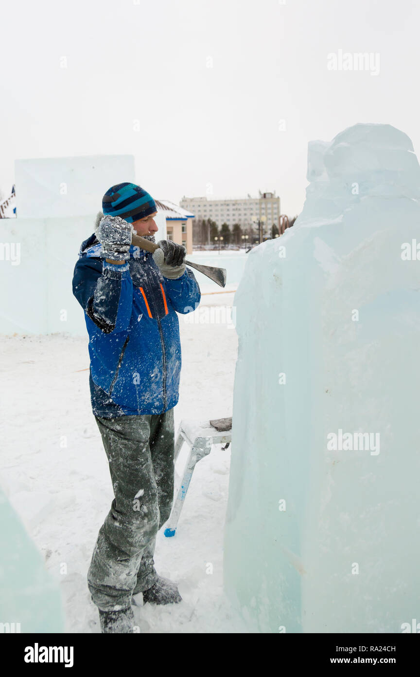 The sculptor cuts an ice figure for Christmas from a block of ice with ...