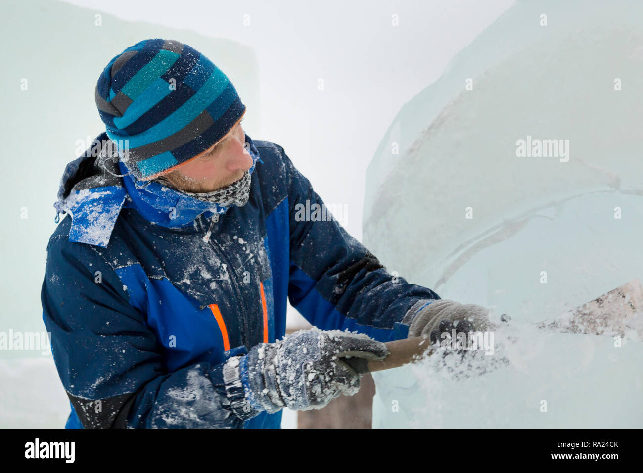The sculptor cuts an ice figure for Christmas from a block of ice with ...