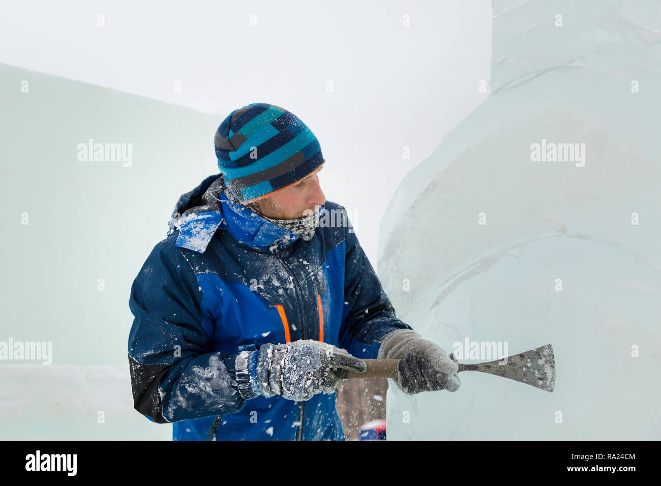 The sculptor cuts an ice figure for Christmas from a block of ice with ...