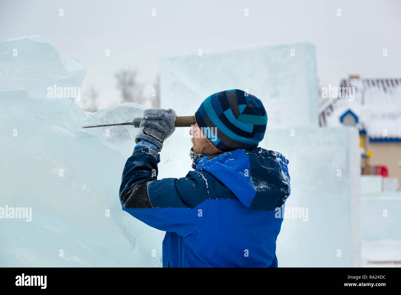 The sculptor cuts an ice figure for Christmas from a block of ice with ...