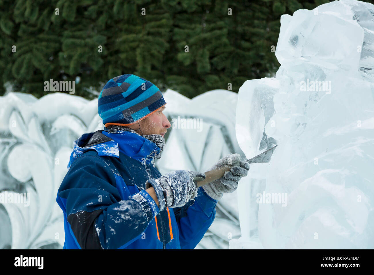 The sculptor cuts an ice figure for Christmas from a block of ice with ...