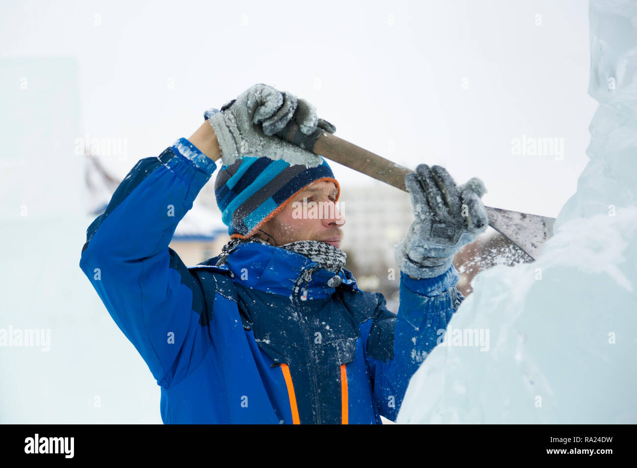 The sculptor cuts an ice figure for Christmas from a block of ice with ...