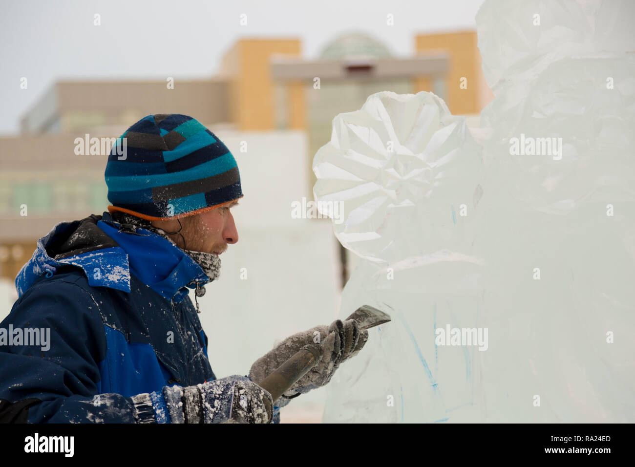 The sculptor cuts an ice figure for Christmas from a block of ice with ...