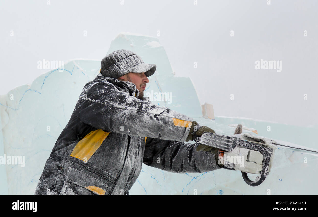 The sculptor cuts ice contours from ice with a chainsaw for Christmas ...