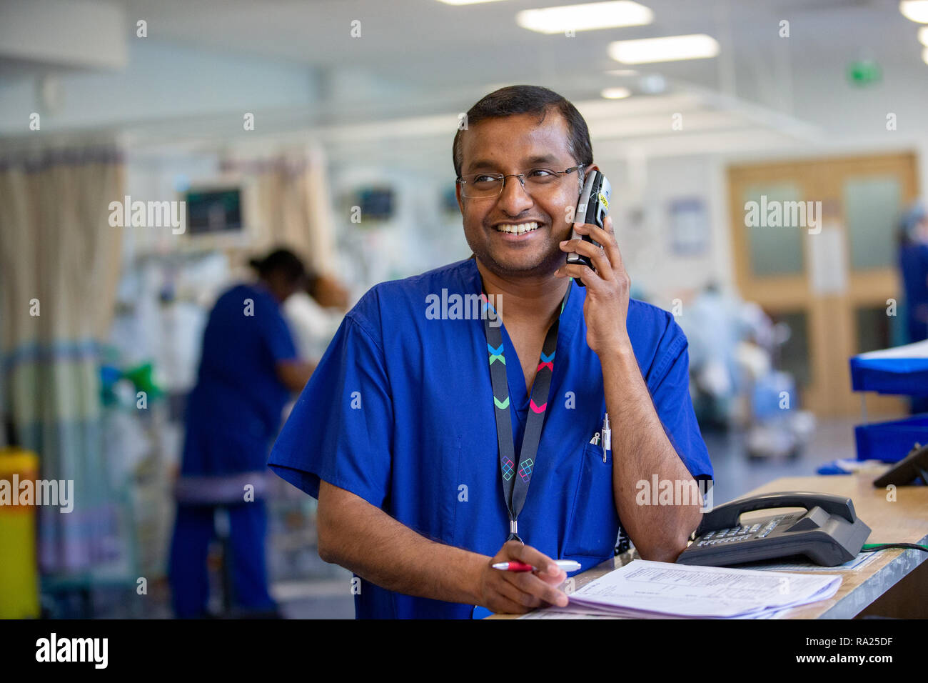 A nurse at a workstation in a hospital ward takes a call from a doctor ...