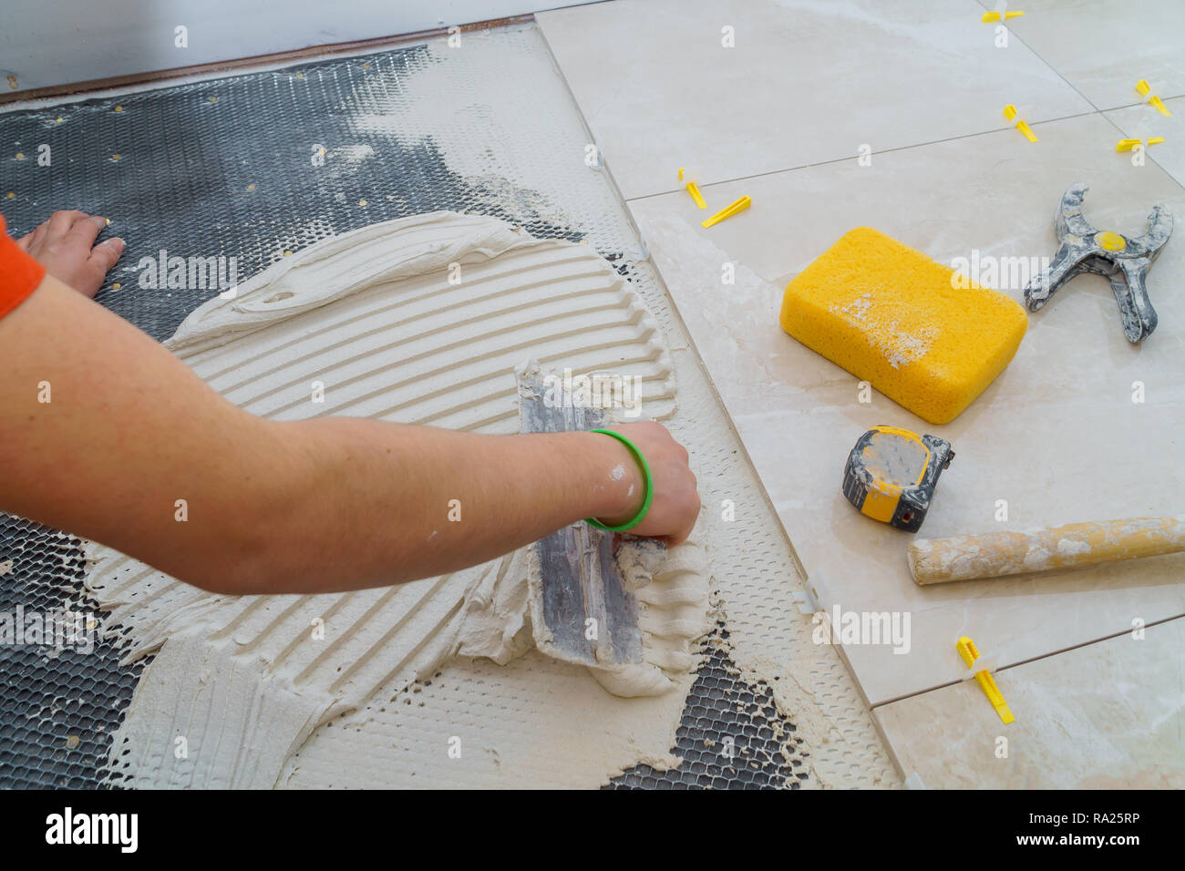 Troweling mortar onto a concrete floor in preparation for laying floor ...