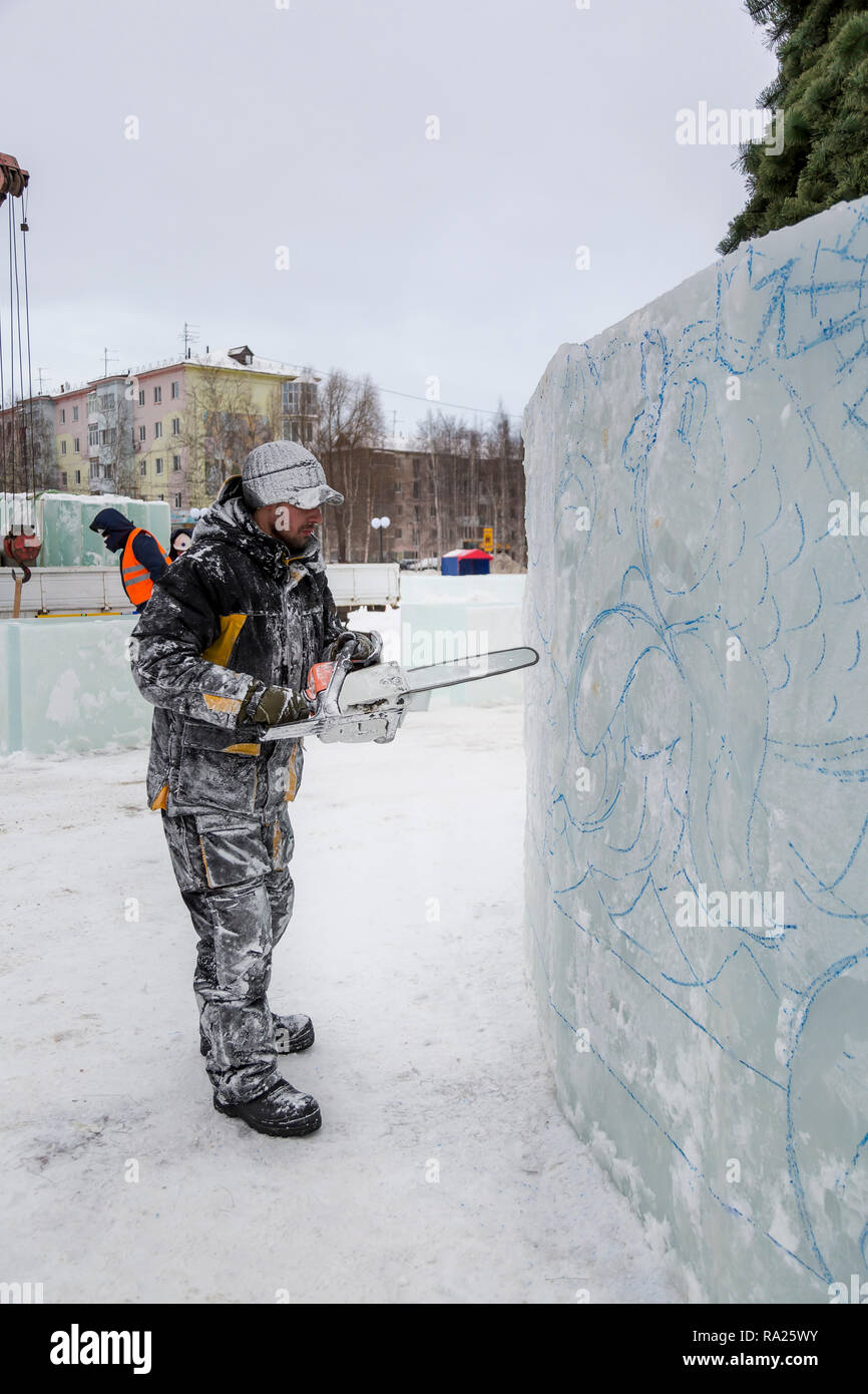 The sculptor cuts ice contours from ice with a chainsaw for Christmas ...