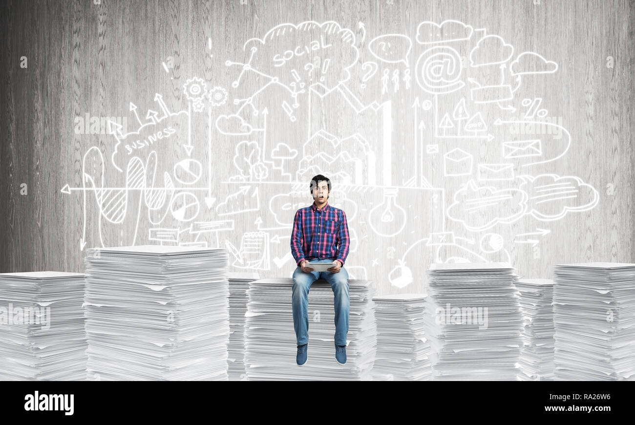 Attractive man sitting on pile of paper documents Stock Photo - Alamy