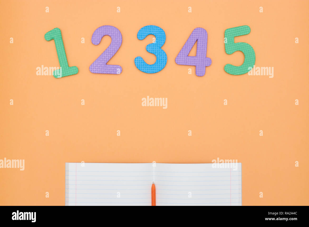 Notebook, pen and colored numbers on orange background. Accessories for ...