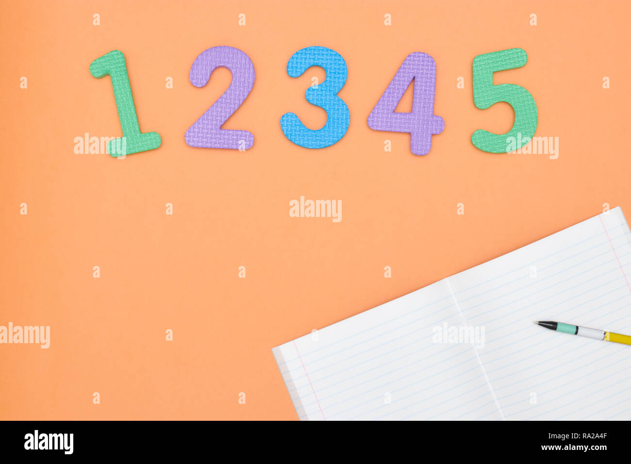Notebook, pen and colored numbers on orange background. Accessories for ...