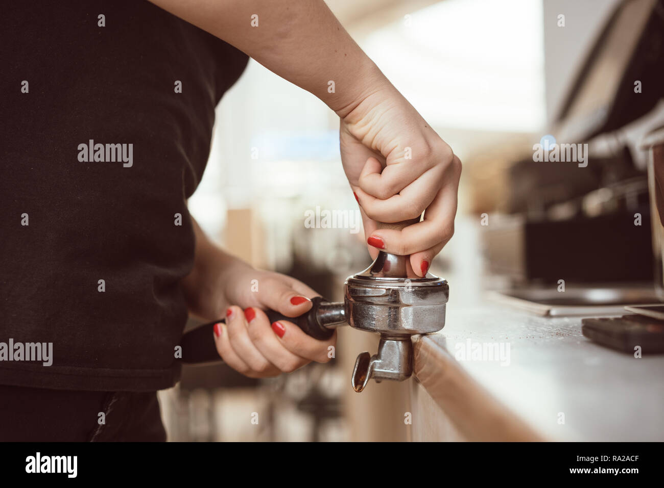 Barista presses ground coffee using tamper. Close-up view on hands ...
