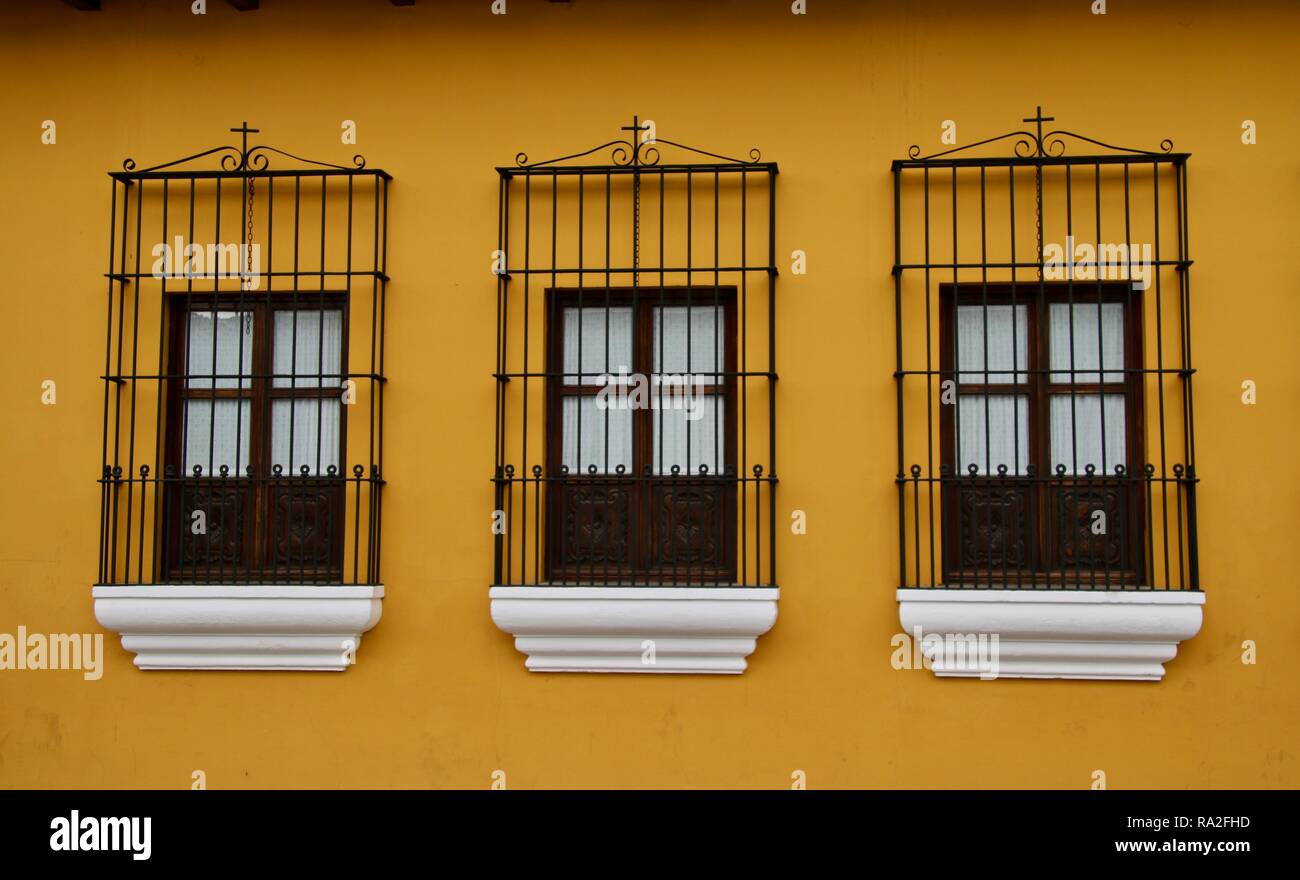 The perfect balance of three wooden windows against a yellow wall with ...