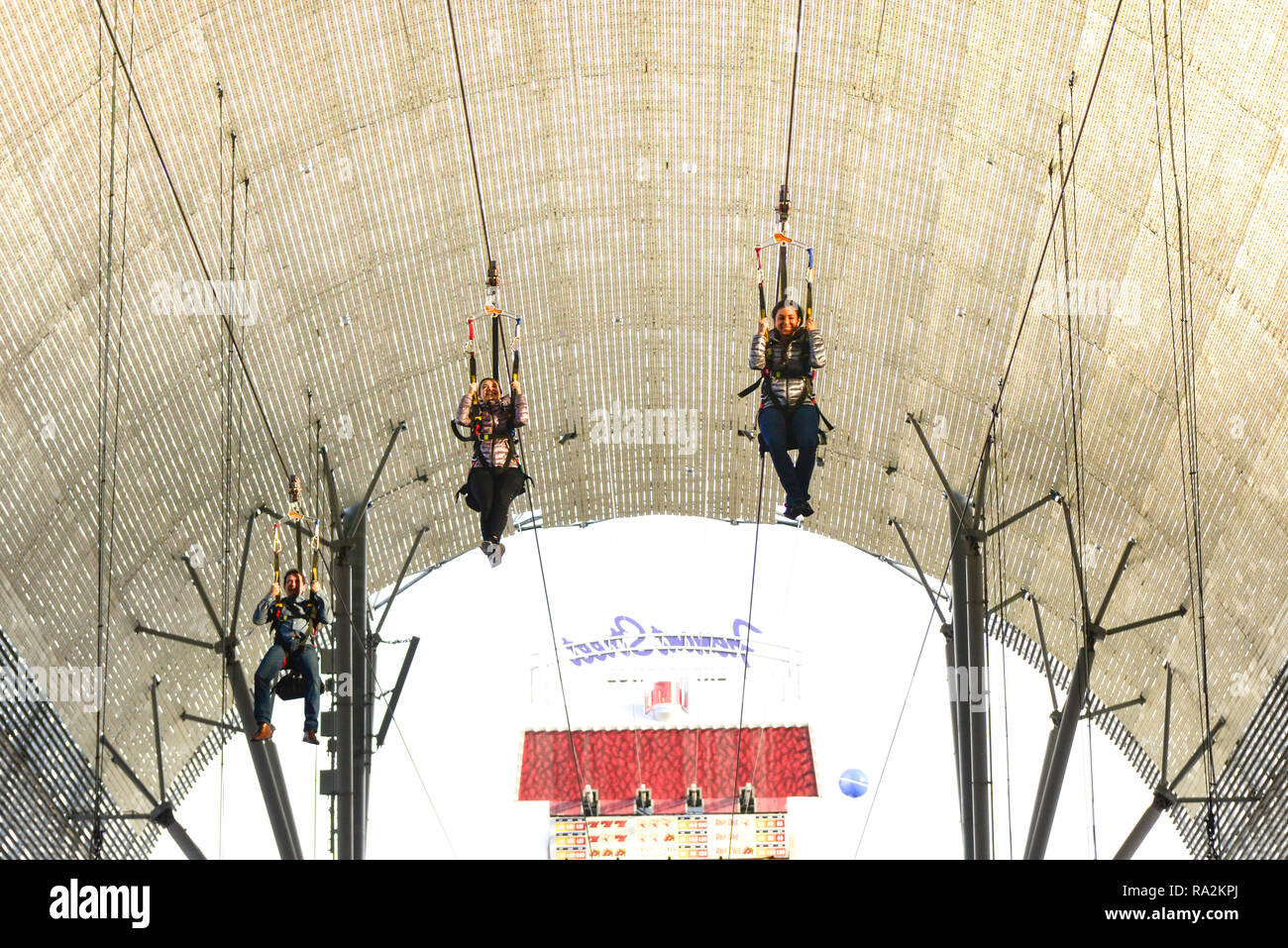 Three people flying on the SlotZilla Zip Line underneath the barrel ...