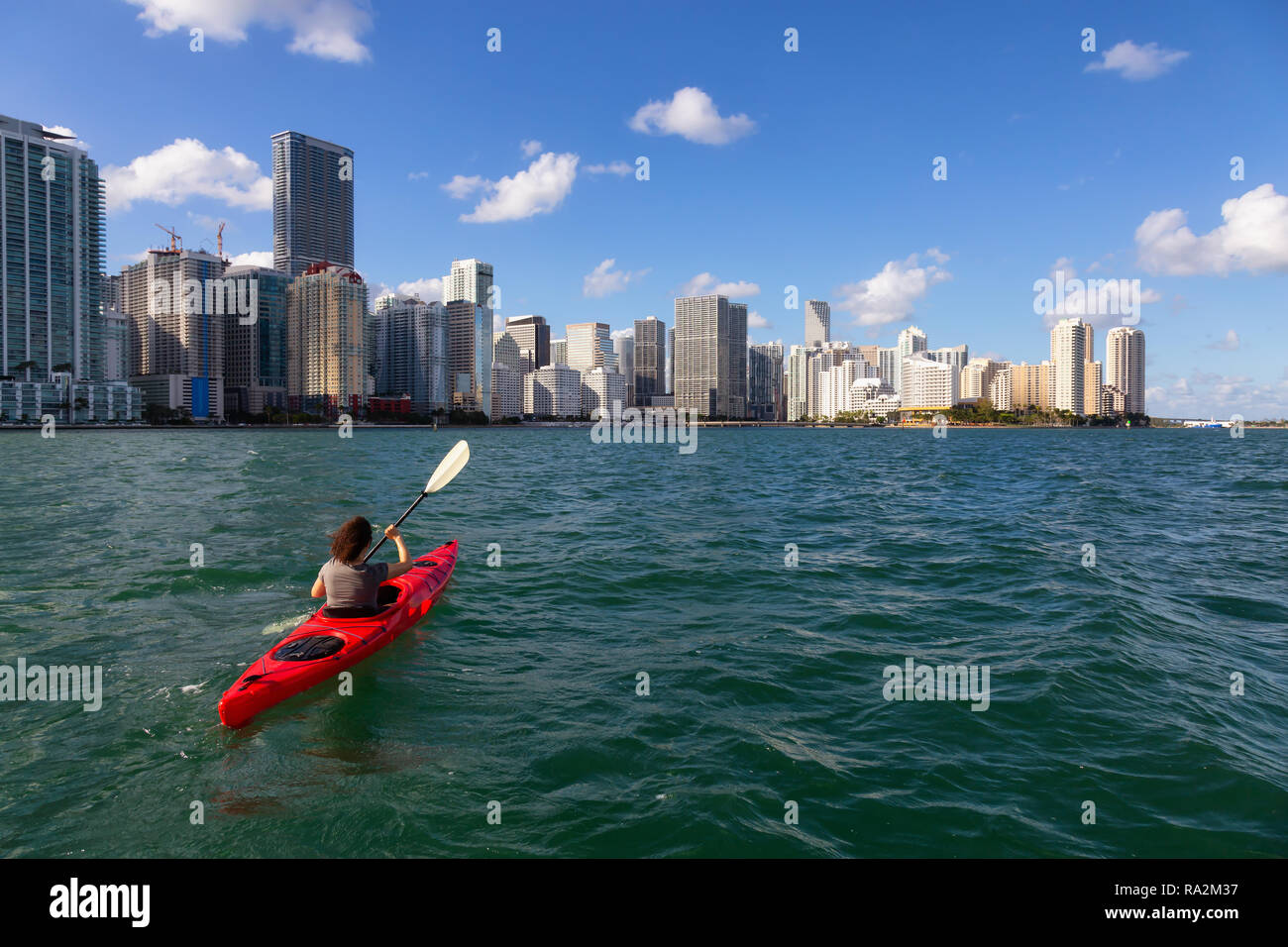 Adventurous girl kayaking in front of a modern Downtown Cityscape ...