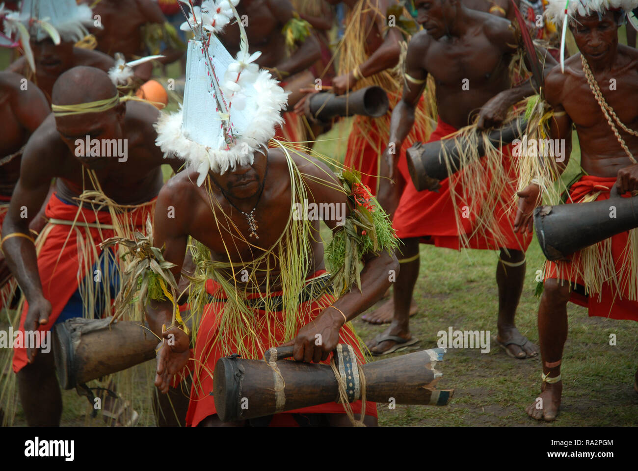 Colourfully dressed and face painted men wearing boat hats dancing as ...