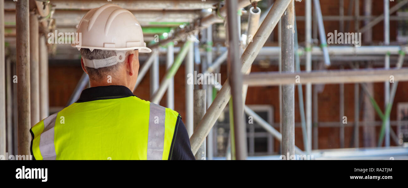 Rear view of male builder construction worker on building site wearing ...