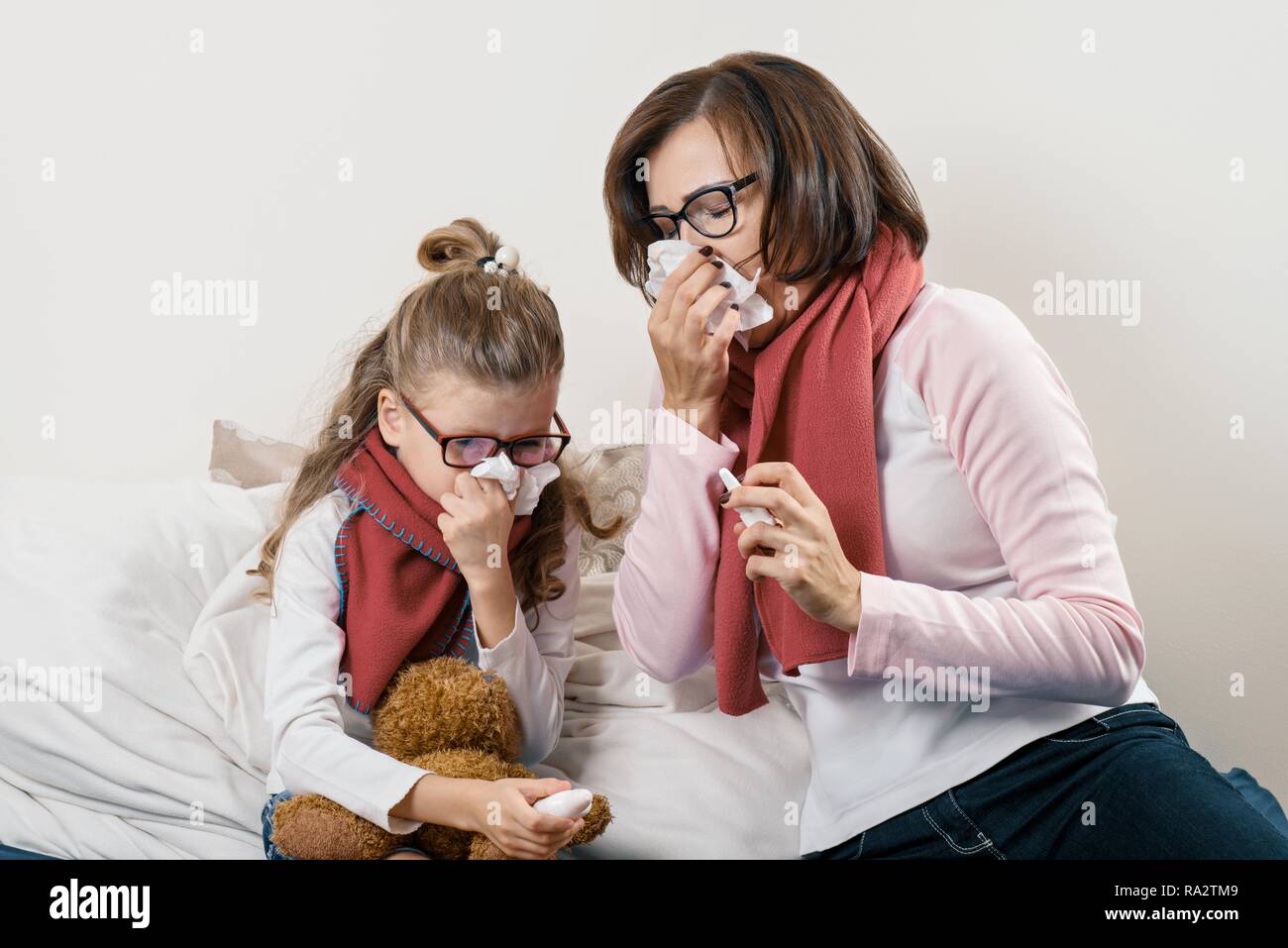Sick mother and child sneezing in handkerchief, holding nasal spray ...