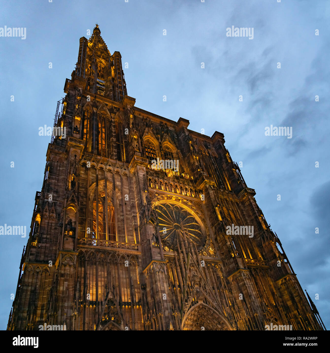 Looking up at the gothic cathedral of Strasbourg illuminated at dusk or ...