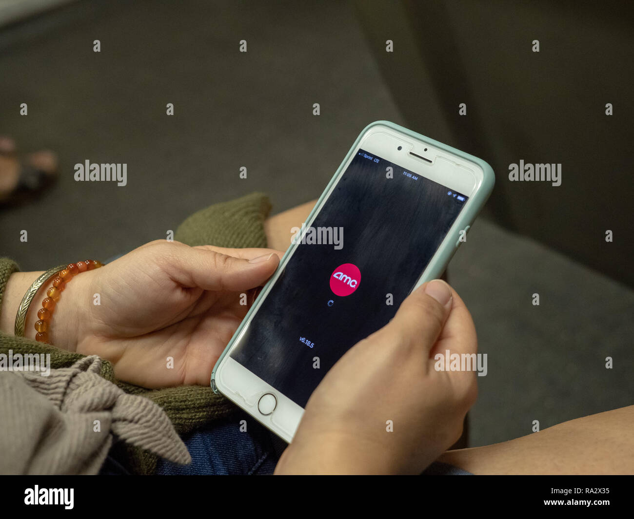 Woman uses AMC movie theater mobile app on iPhone while commuting on ...