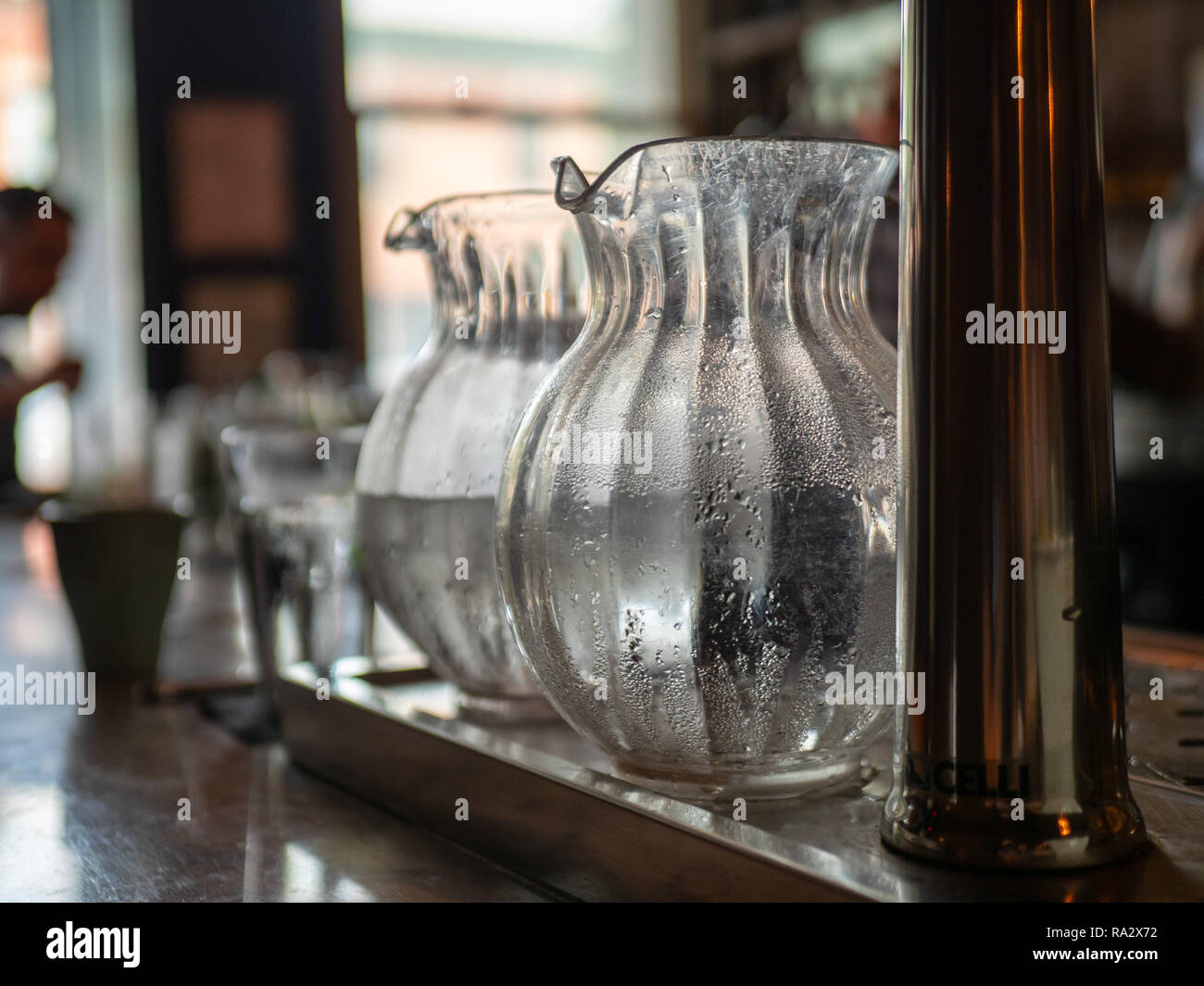 Two glass water pitchers with condensation sitting on bar counter Stock ...