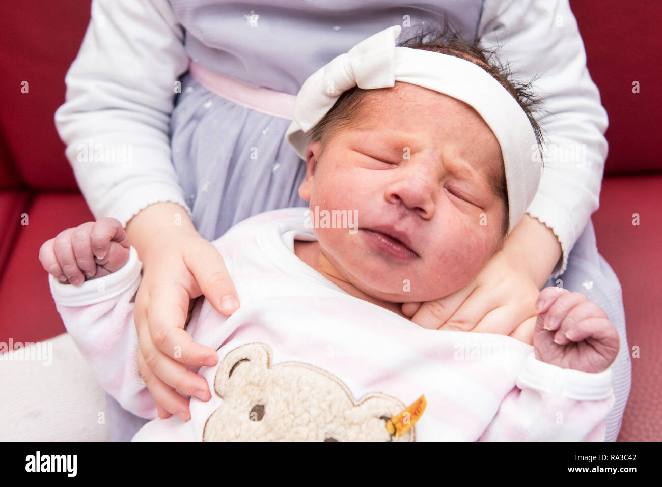 01 January 2019, Hamburg: Little Elena is being held by her sister ...