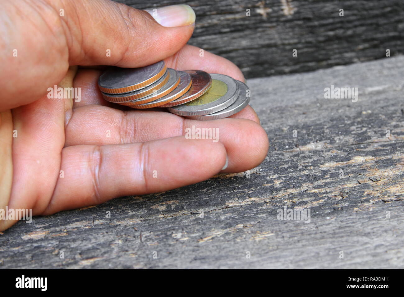 coin money in people hand on wooden floor background Stock Photo - Alamy
