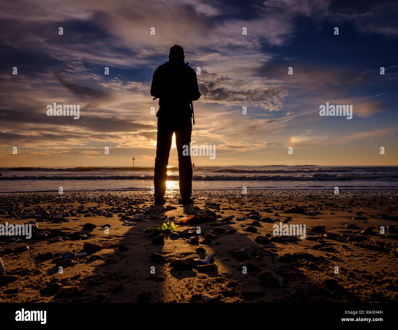 The silhouette of a walker standing on West Wittering beach in mid ...