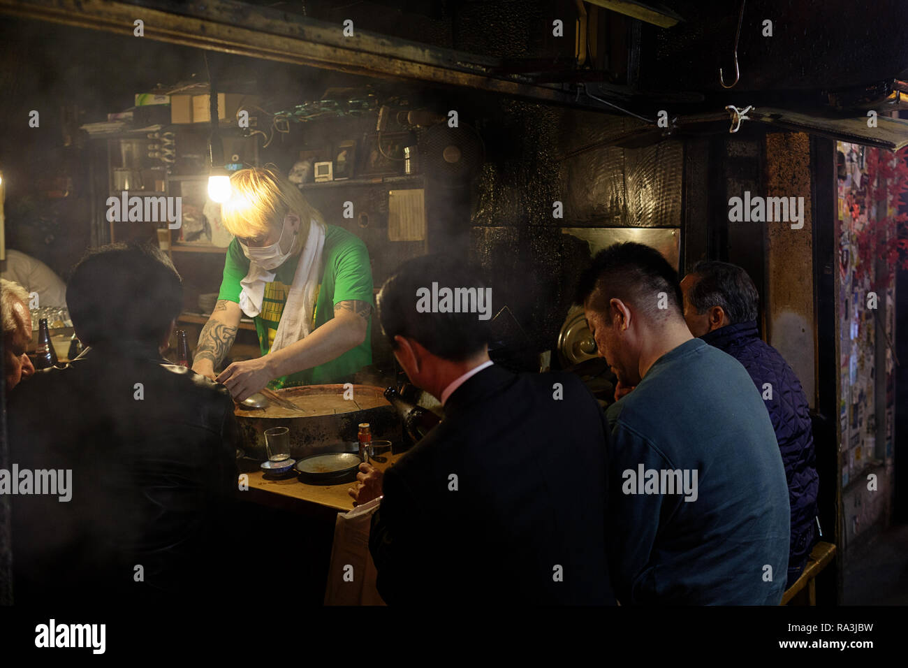 A Japanese chef cooks at Hot and smoky Tokyo street restaurant, as ...