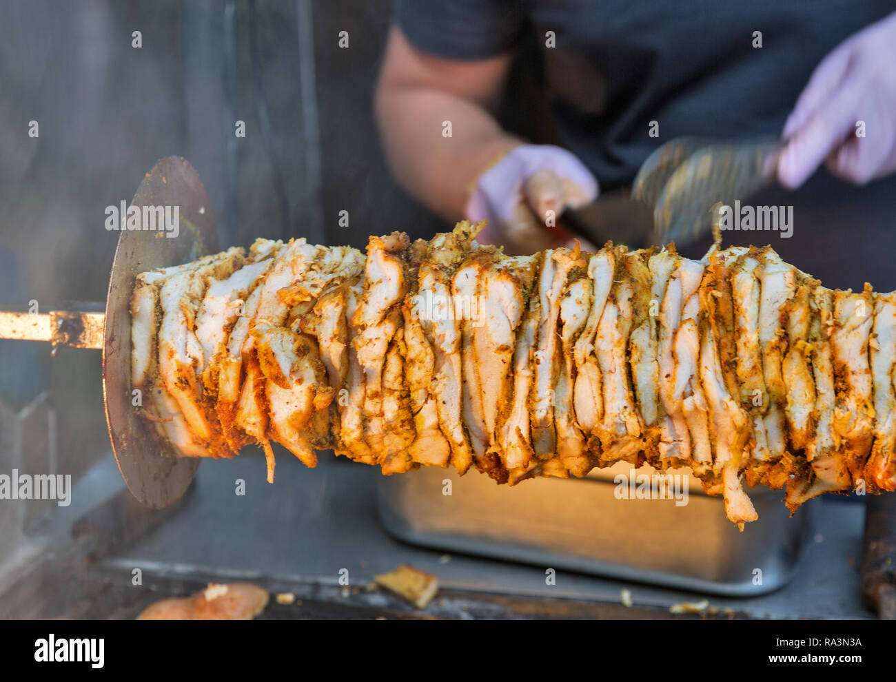 Cooking shawarma, meat layers strung on a skewer, chopped meat is on ...