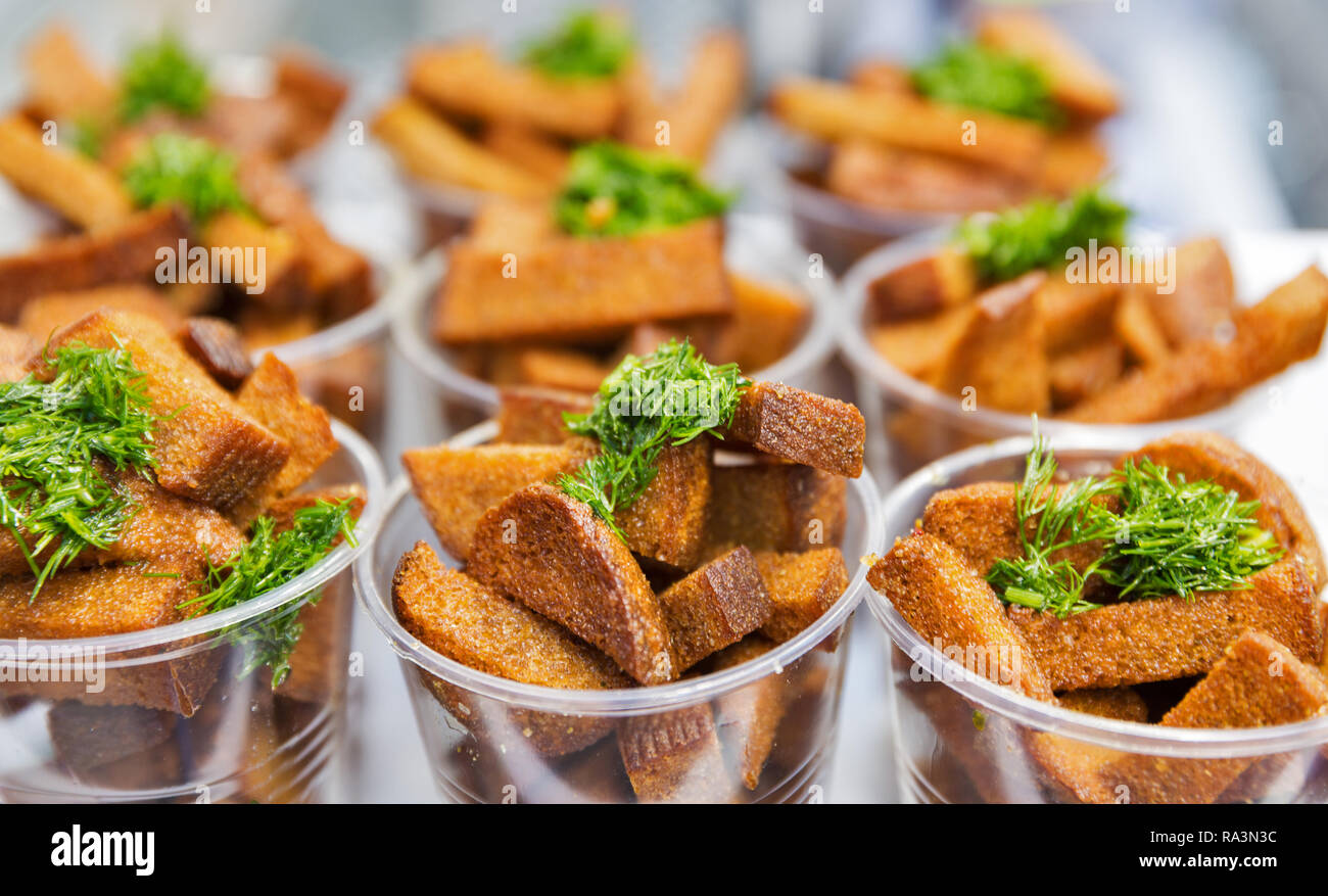 Rye bread garlic croutons with dill as a snack closeup in plastic cups ...