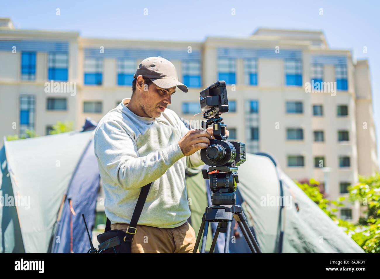 a professional cameraman prepares a camera and a tripod before shooting ...