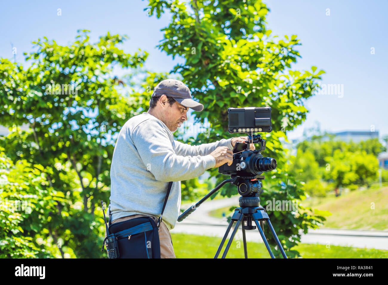 a professional cameraman prepares a camera and a tripod before shooting ...
