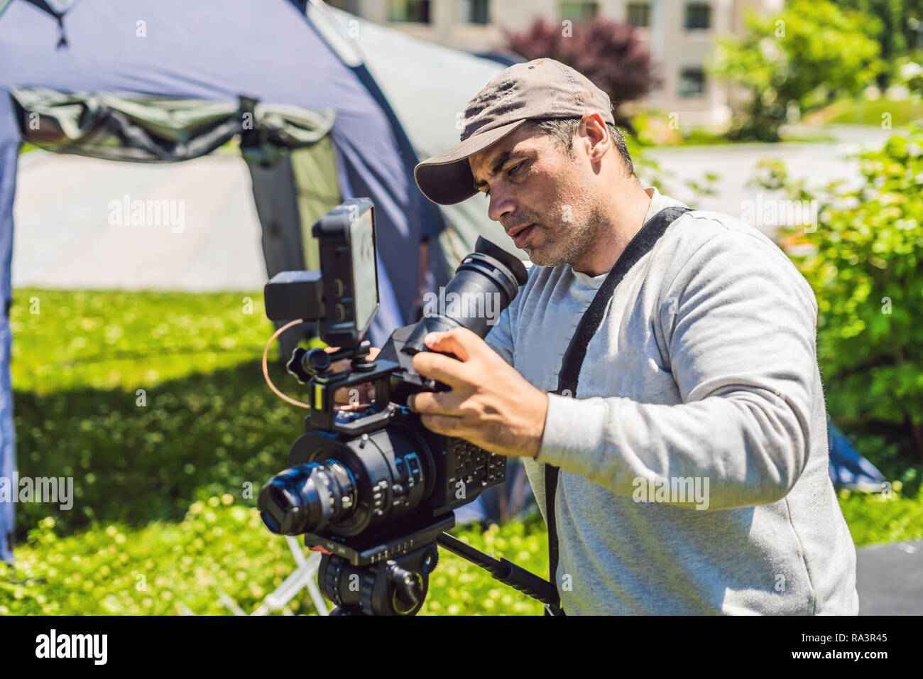 a professional cameraman prepares a camera and a tripod before shooting ...