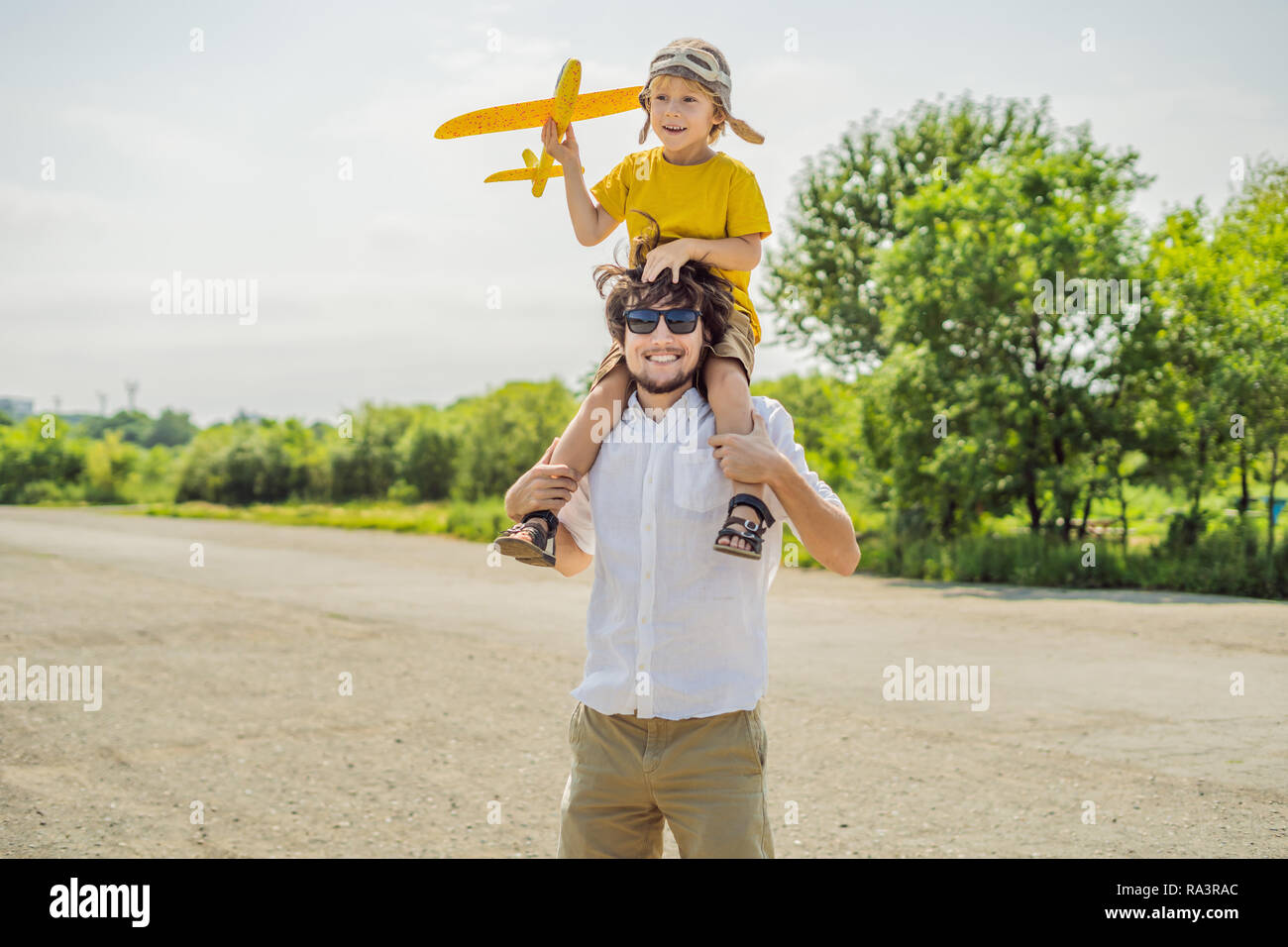 Happy father and son playing with toy airplane against old runway ...
