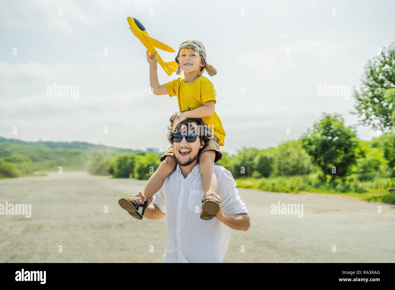 Happy father and son playing with toy airplane against old runway ...
