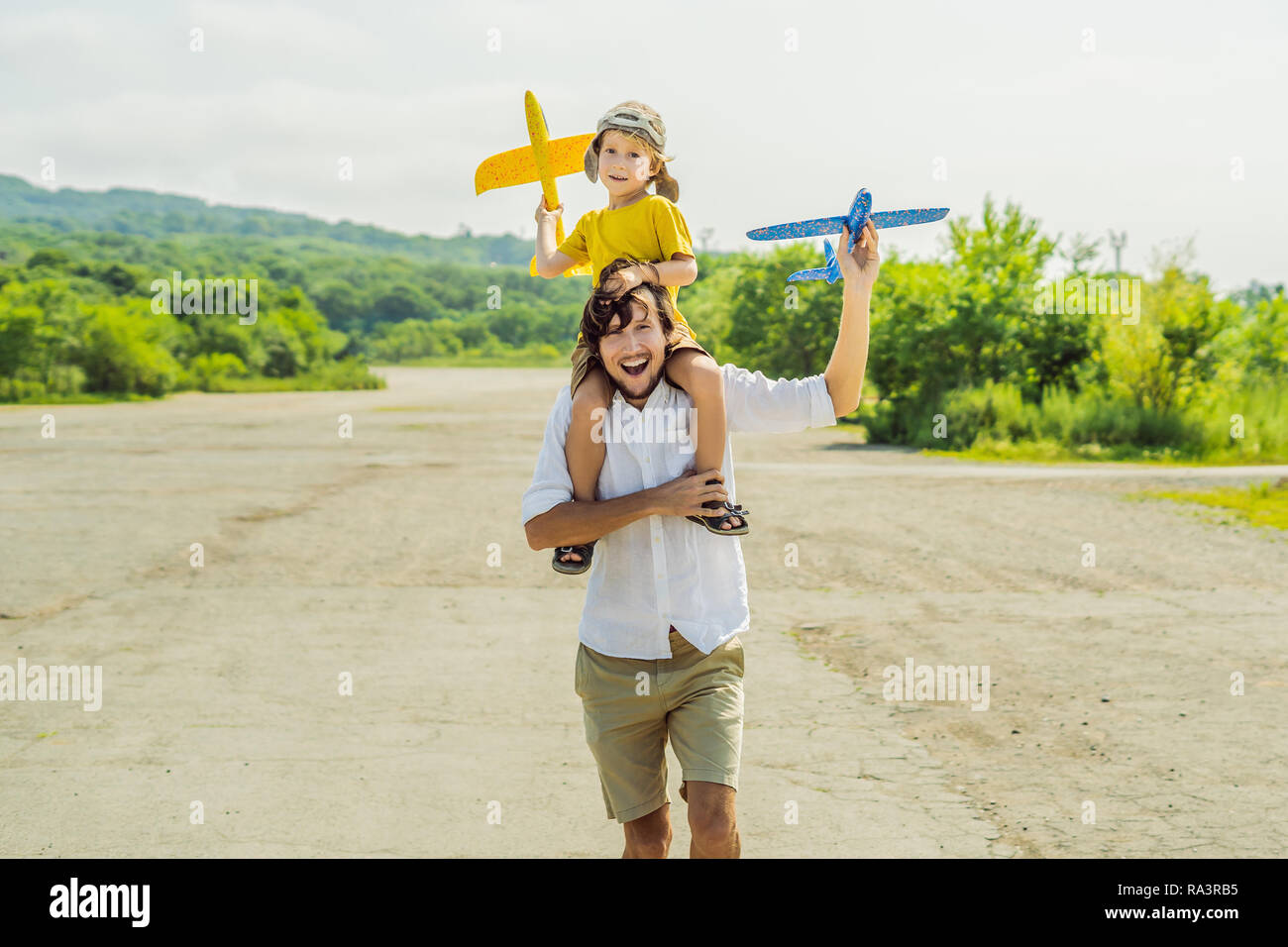 Happy father and son playing with toy airplane against old runway ...