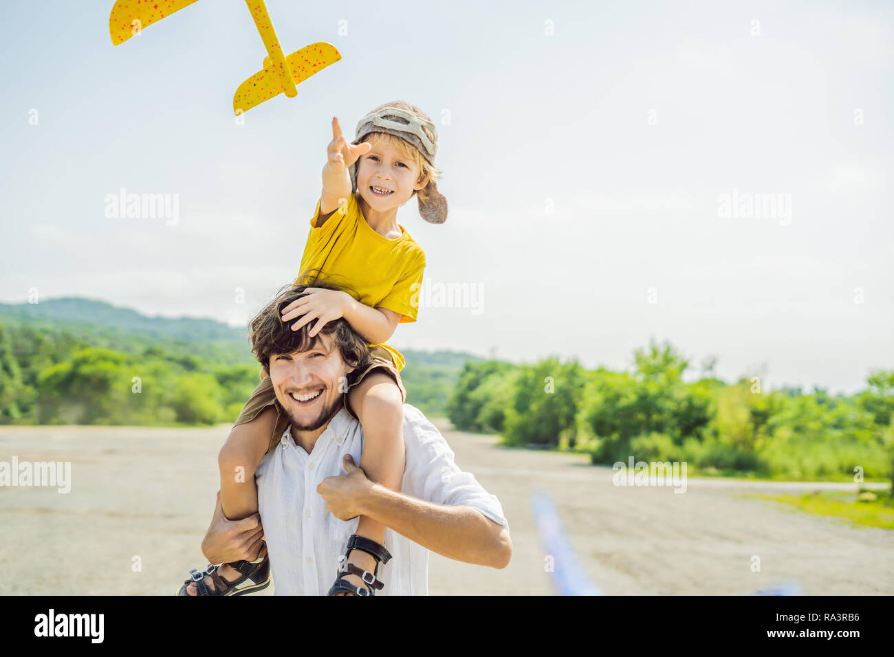 Happy father and son playing with toy airplane against old runway ...