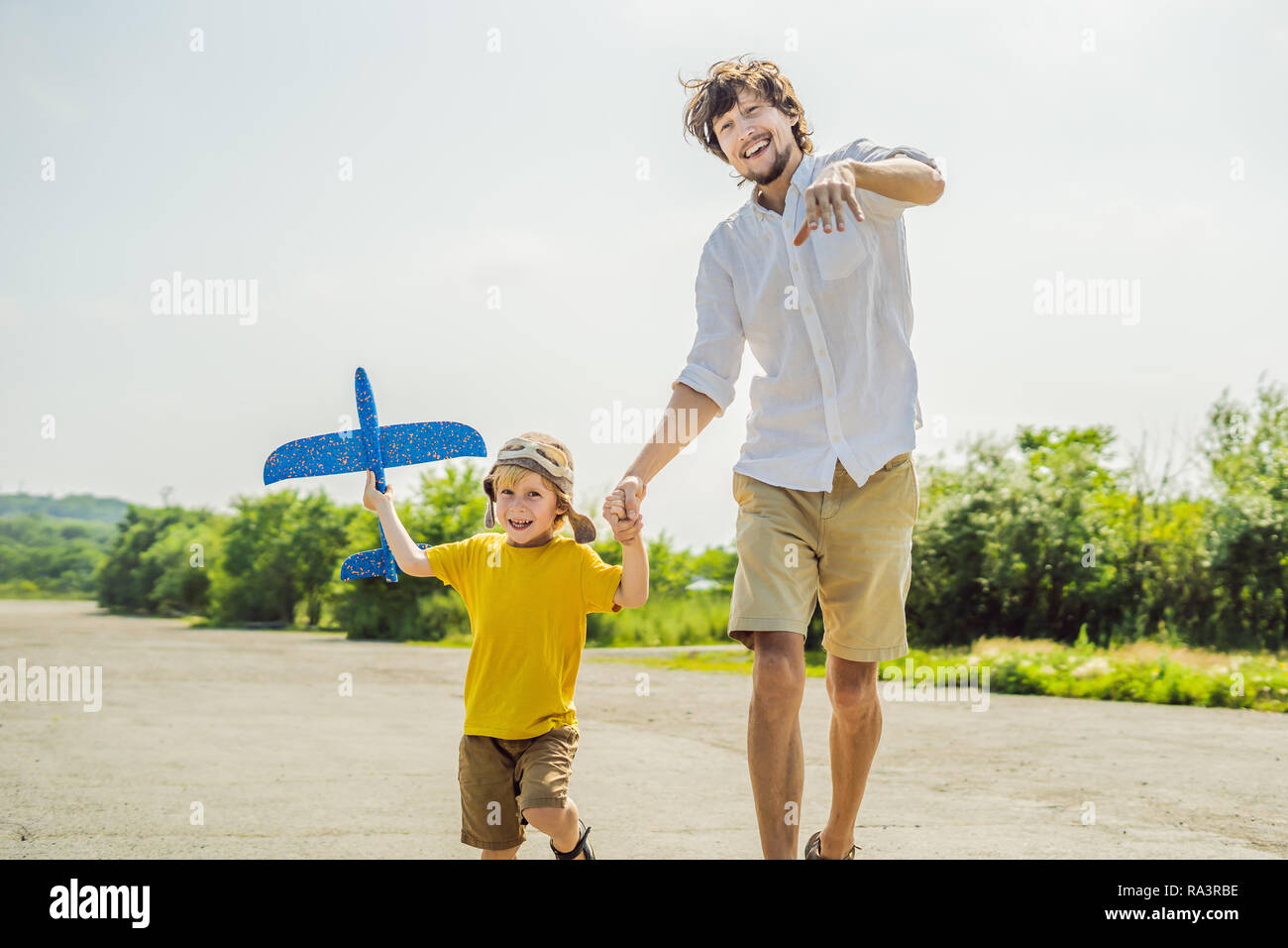 Happy father and son playing with toy airplane against old runway ...