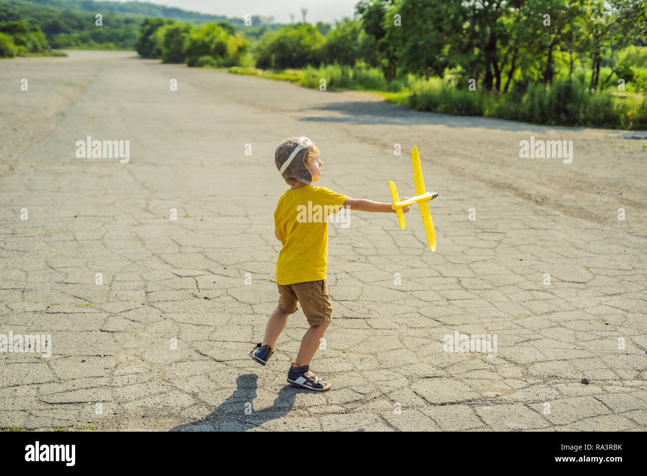 Happy kid playing with toy airplane against old runway background ...