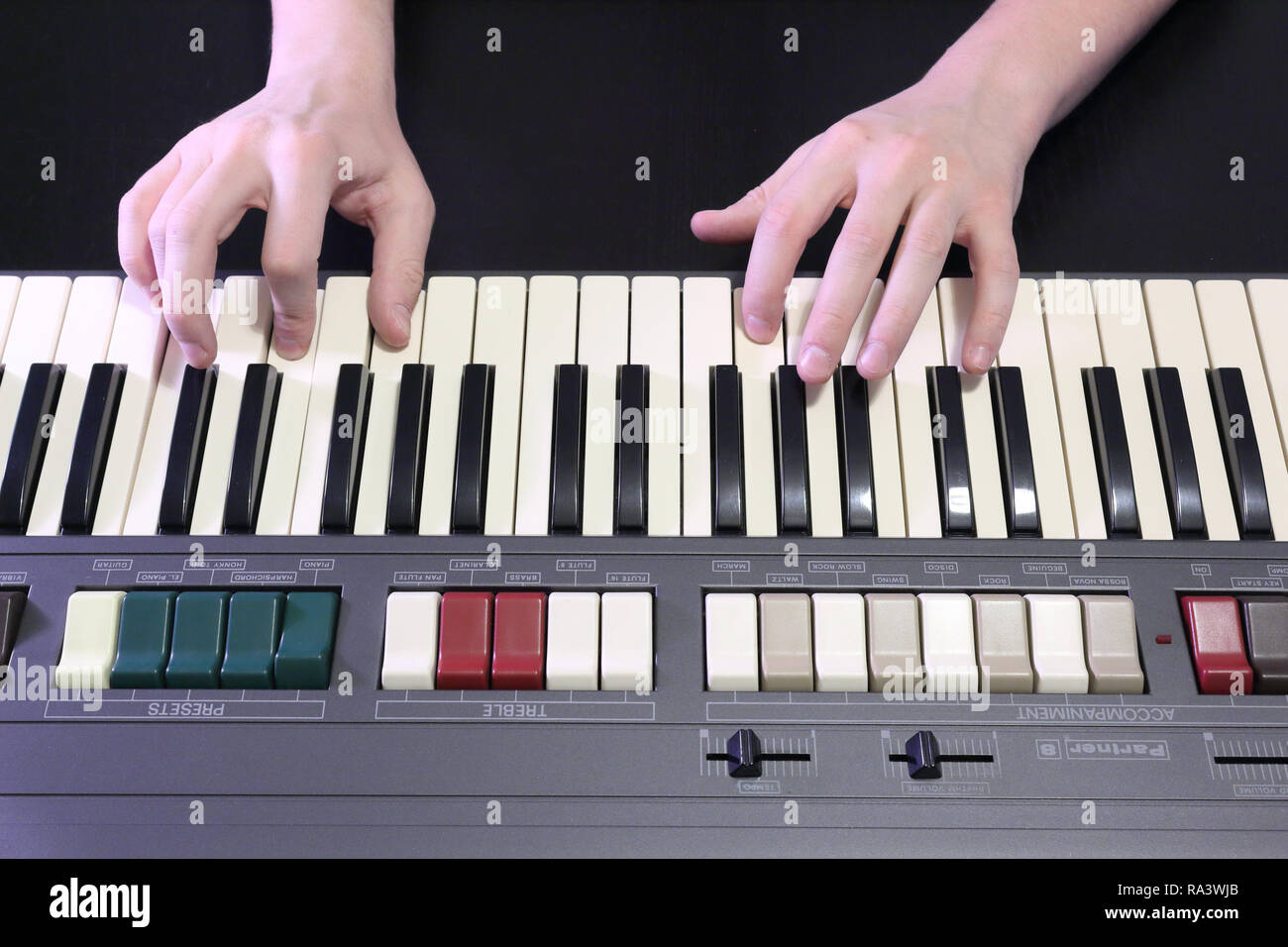 A right hand playing a A (LA) major chord on an old black piano with ...