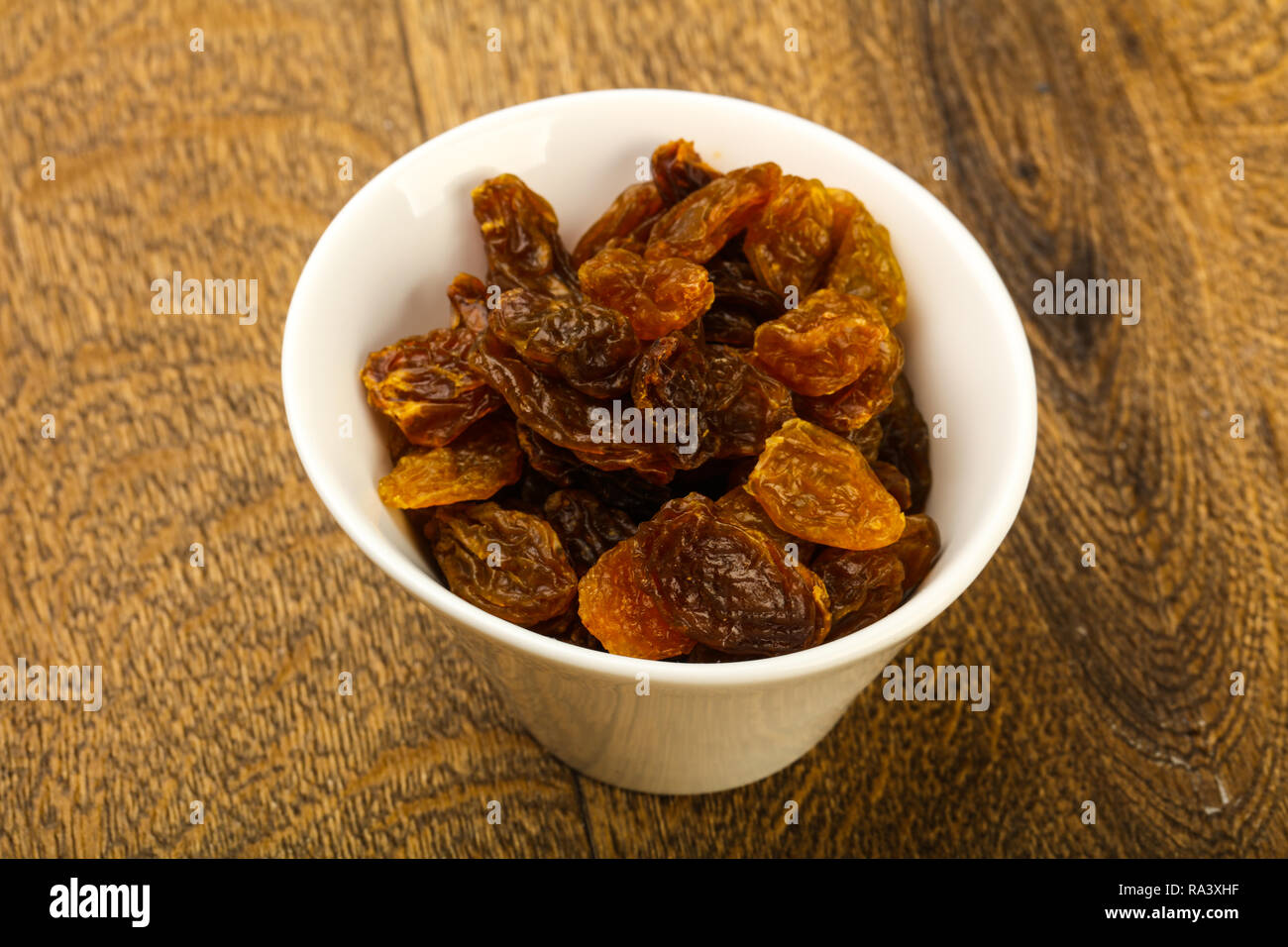 Dry Raisin in the bowl over the wooden background Stock Photo - Alamy